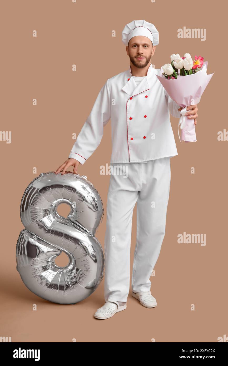Young male chef with balloon in shape of figure 8 and flowers on beige ...