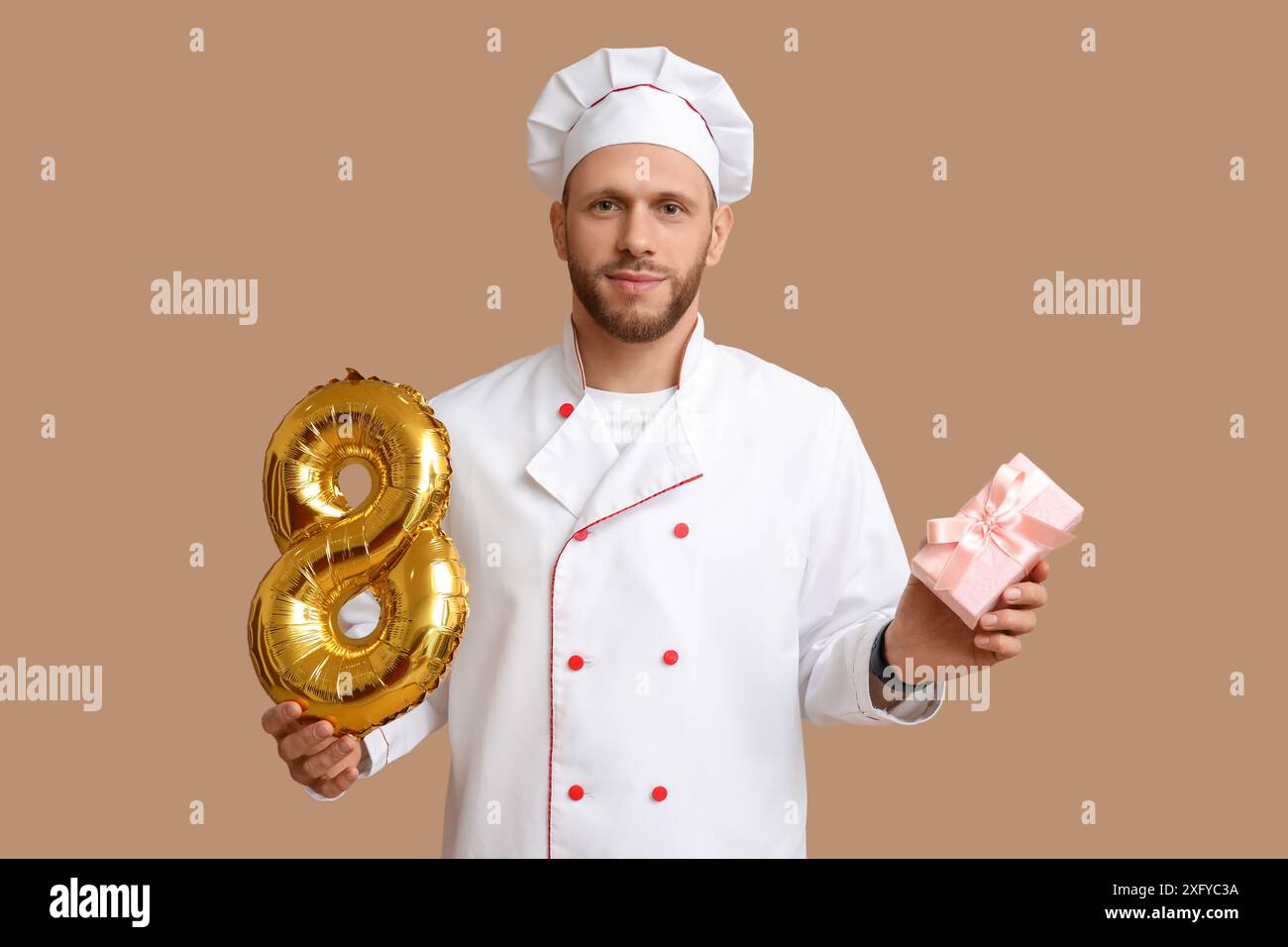 Young male chef with balloon in shape of figure 8 and gift box on beige ...
