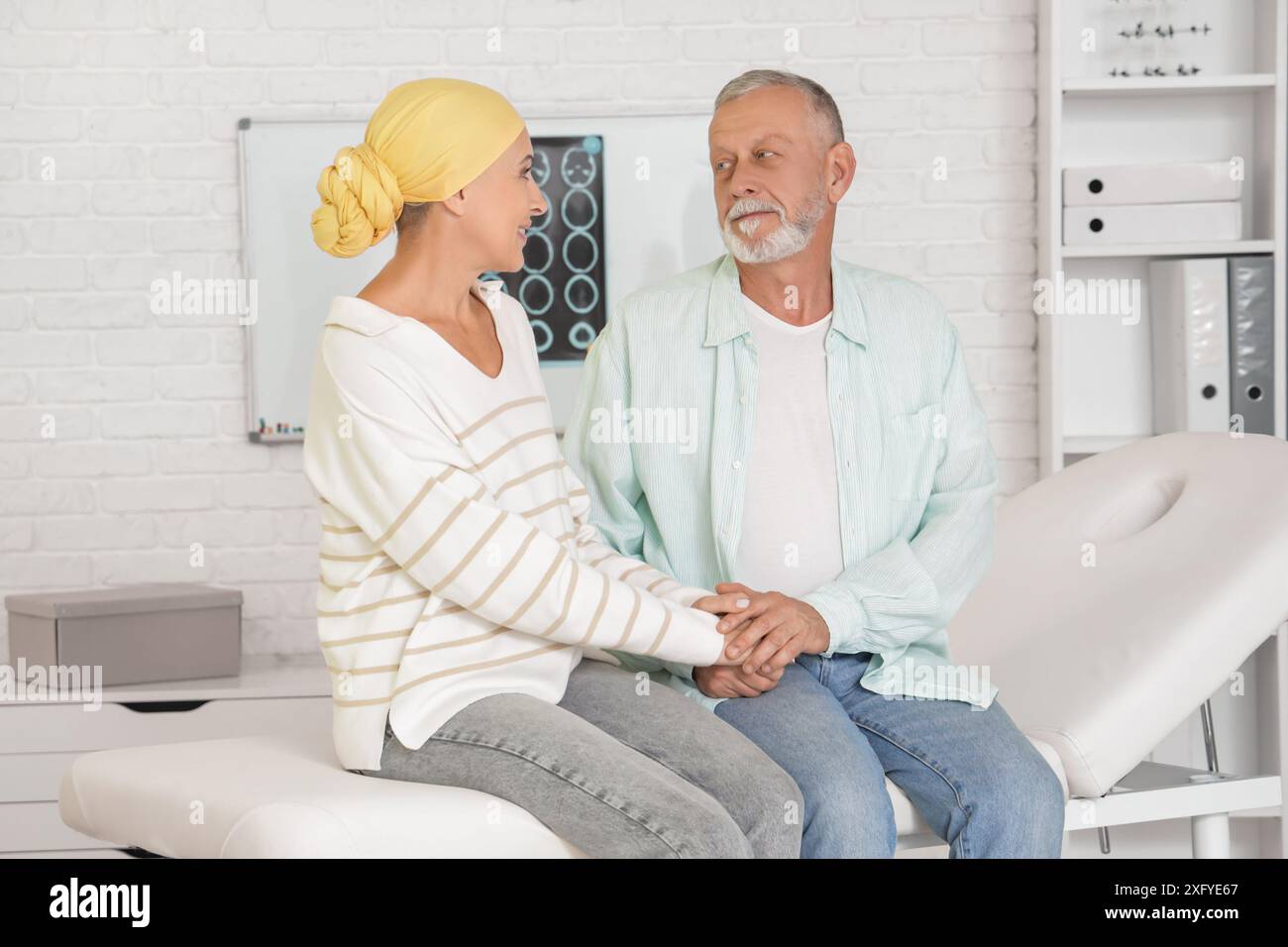 Mature woman after chemotherapy with her husband sitting on couch in ...