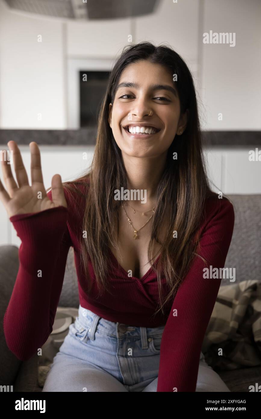 Positive beautiful young adult Indian influencer girl waving greeting ...