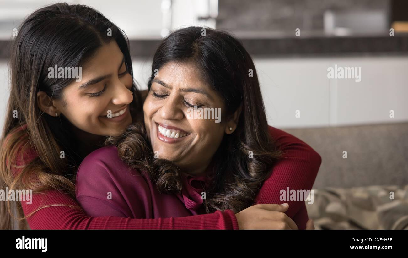 Positive loving adult Indian kid hugging cheerful laughing mature mum ...