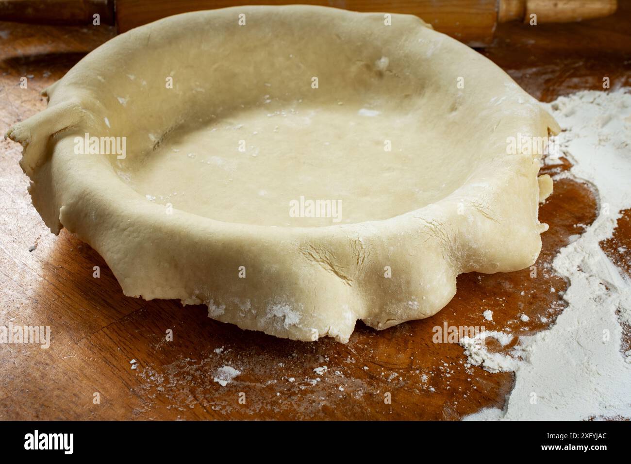 Making a pie. Rolled dough placed over a pie shell. Top side view with ...