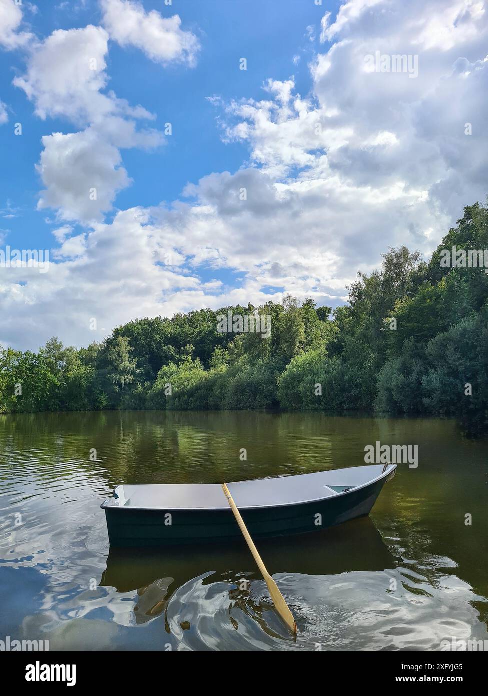 An empty canoe floats alone on the lake, clouds forming in the sky on a ...