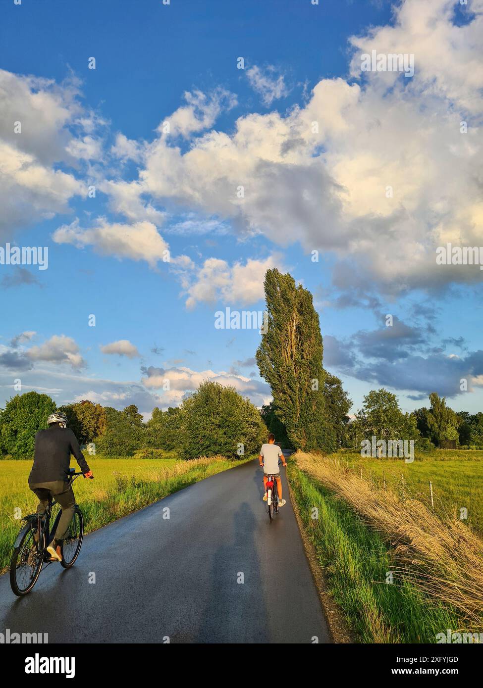 A young cyclist takes a short break on the right side of an empty road ...