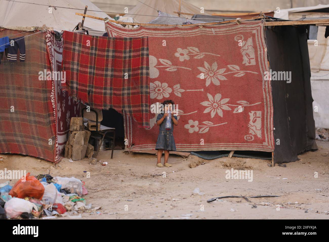 Palestinian children walk past tents housing people who lost their ...