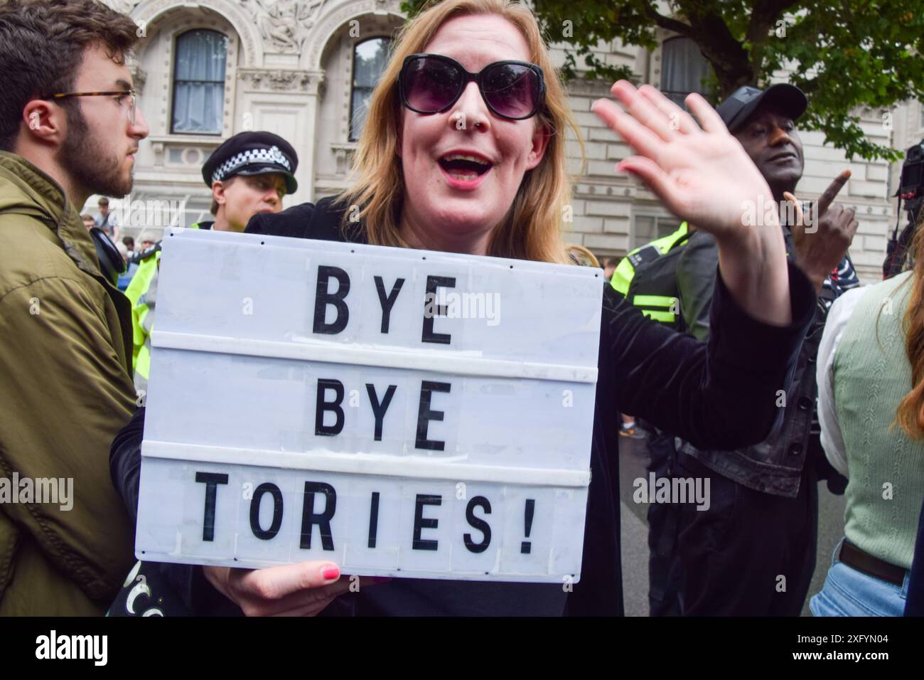 London, UK. 5th July 2024. An activist holds an anti-Tory sign. Crowds ...