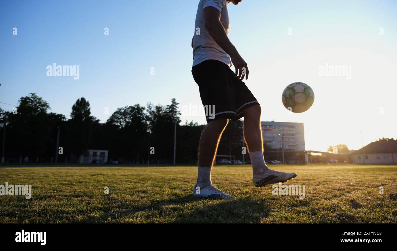 Legs of young man kicking ball at green field. Male feet of ...