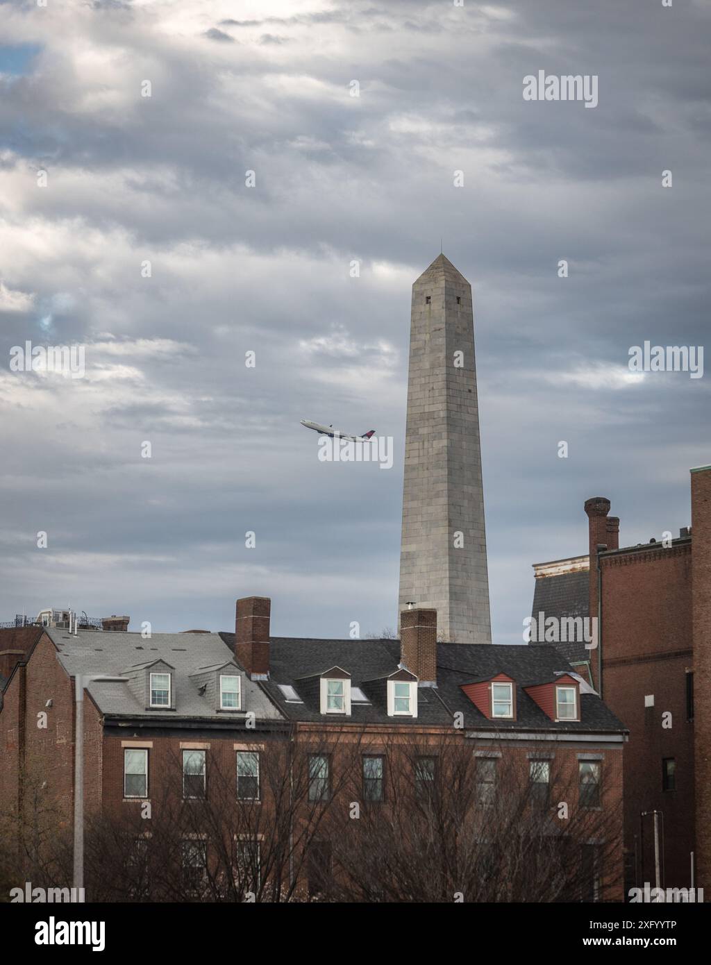 A scenic view of the Bunker Hill Monument with an airplane flying in ...