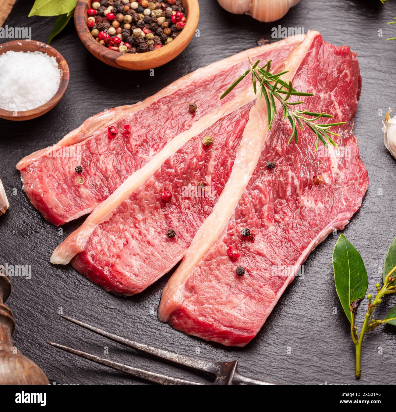 Sliced picanha beef with spices and herbs on a gray stone serving board ...