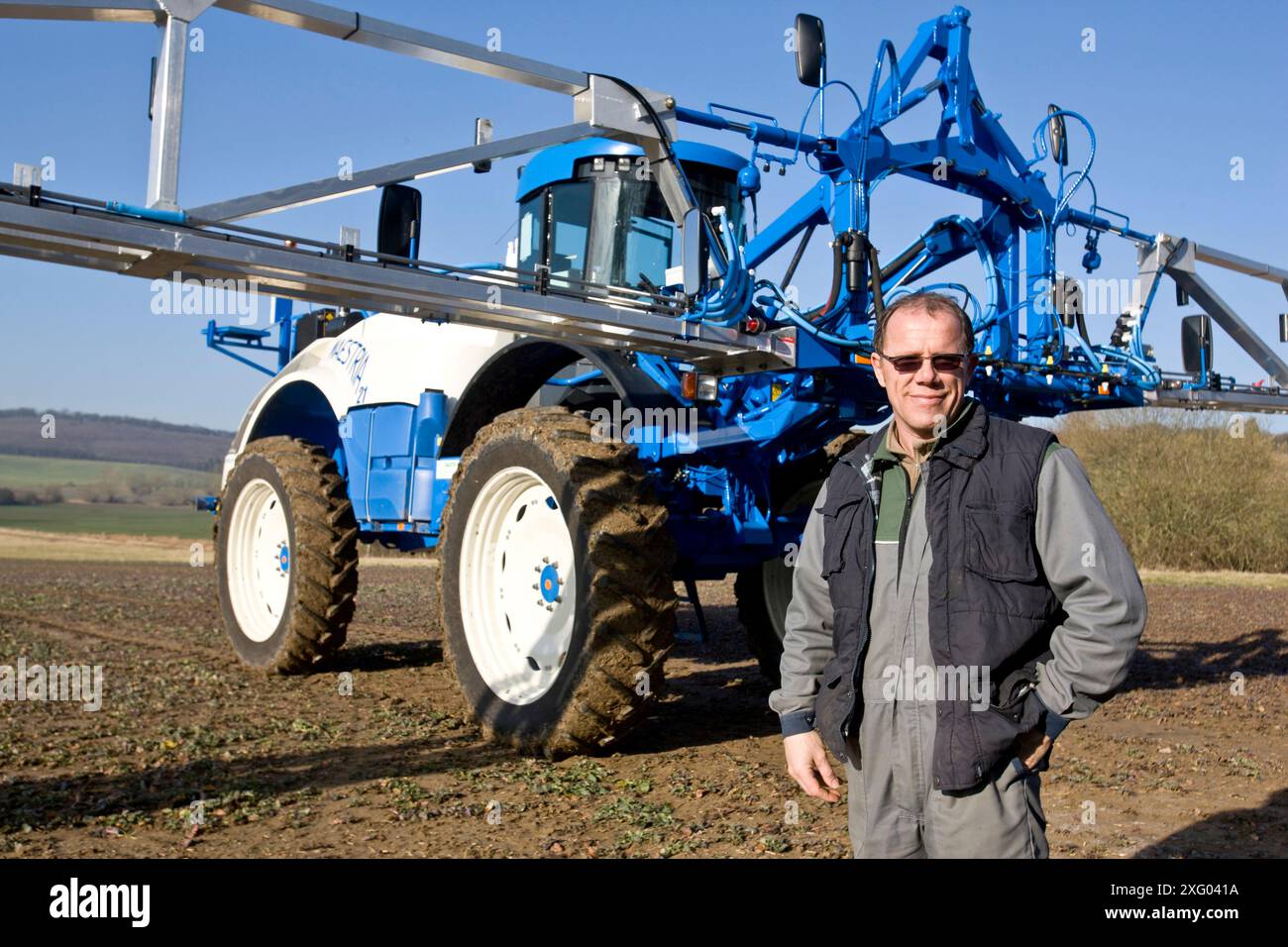 45-year-old farmer smiling in a field in front of his self-propelled ...