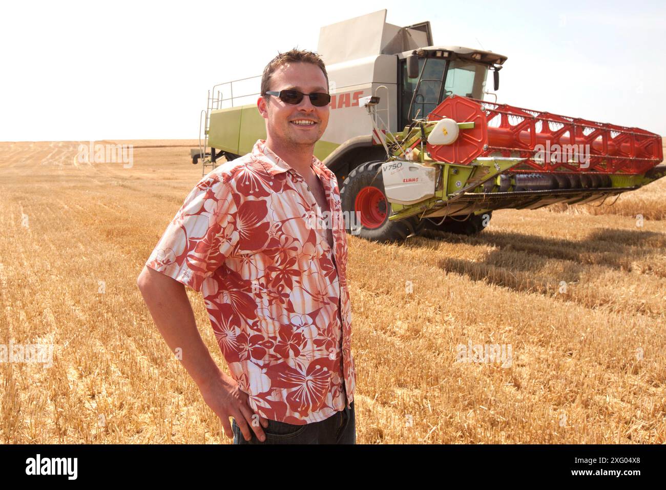 Barley harvesting with a 7.5 m wide claas machine. Young farmer ...