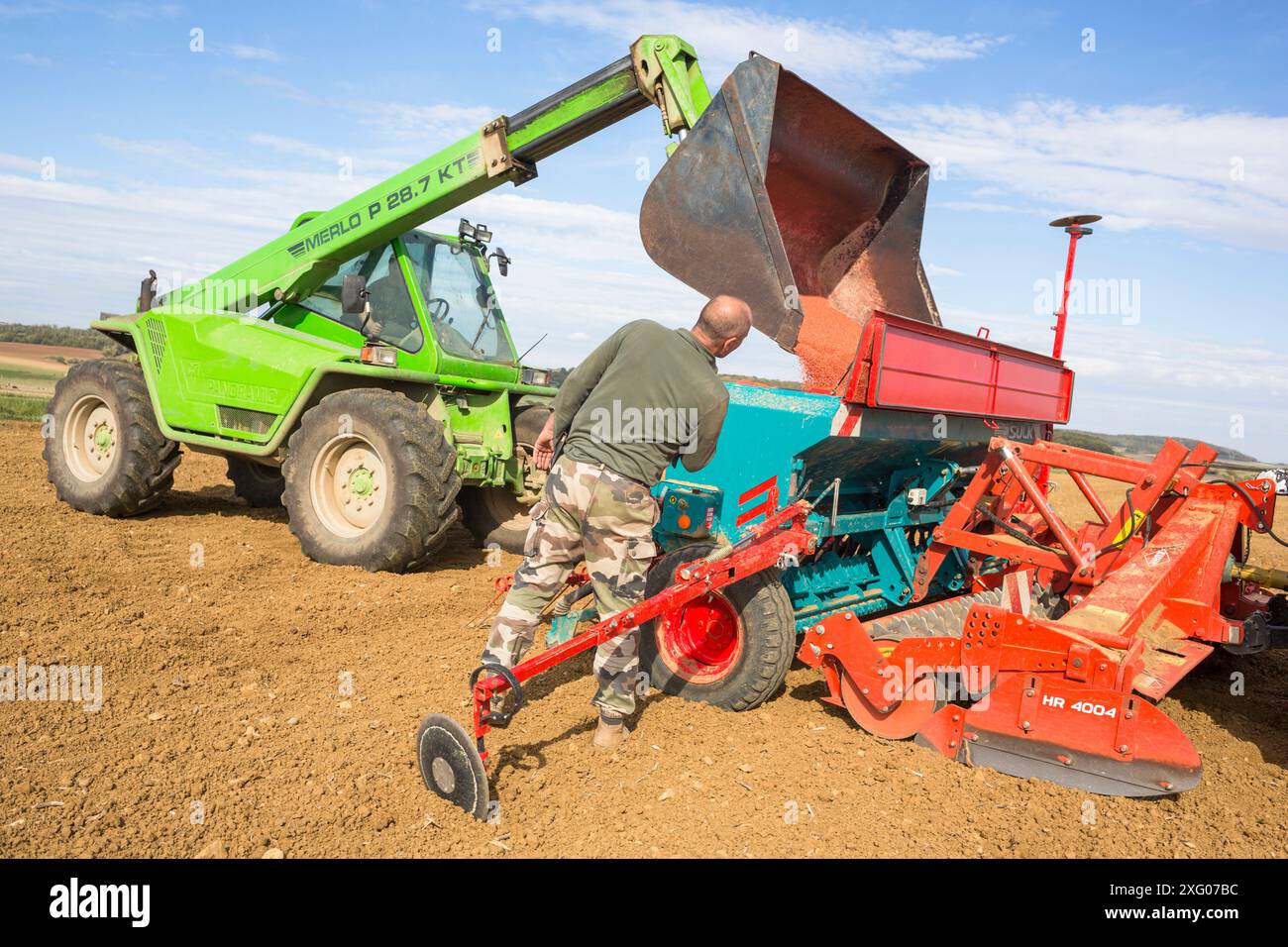 Farmer sowing wheat or barley with a sulky combination seed drill ...
