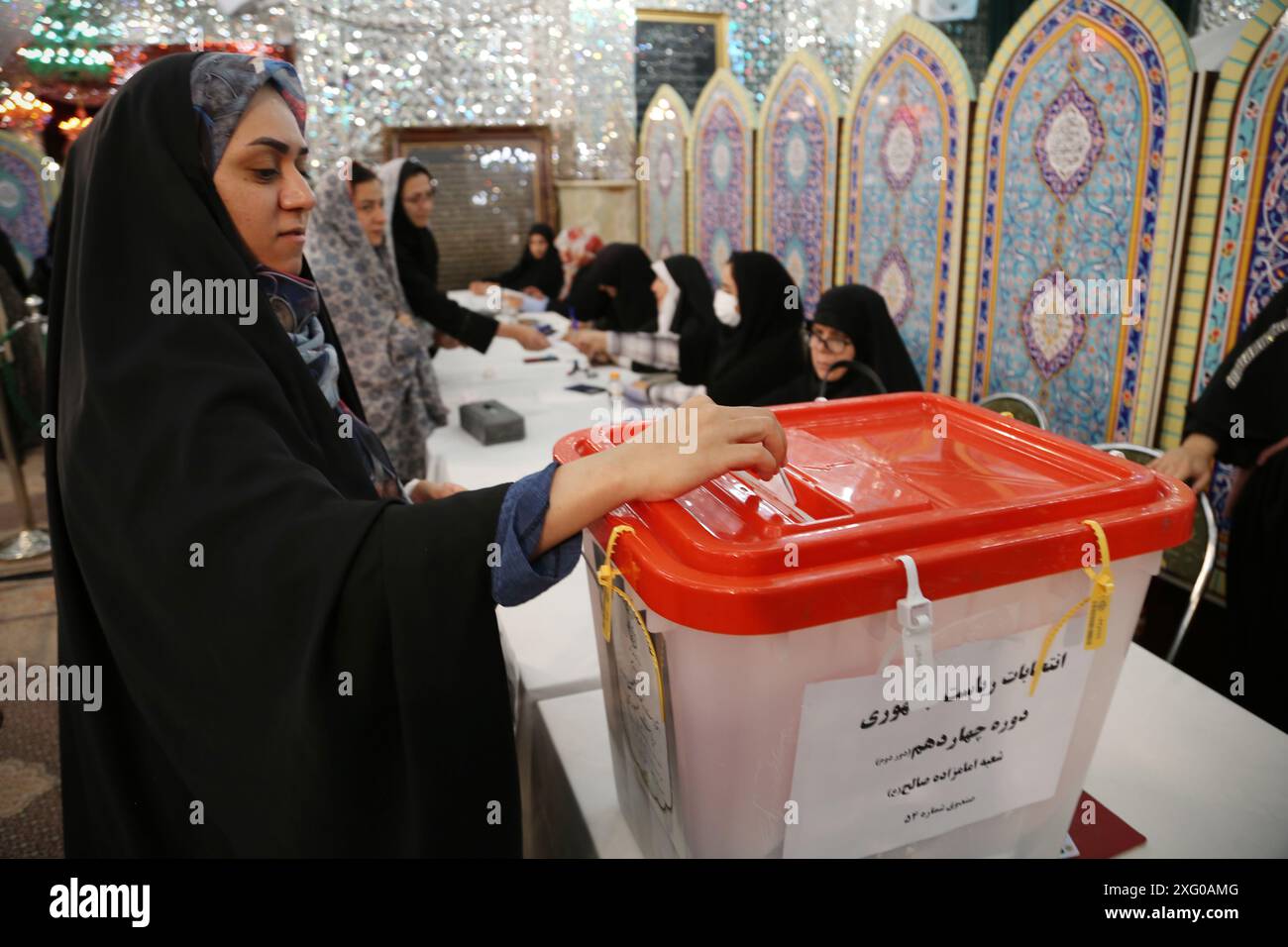 Tehran, Iran. 5th July, 2024. An Iranian veiled woman casts her ballot ...