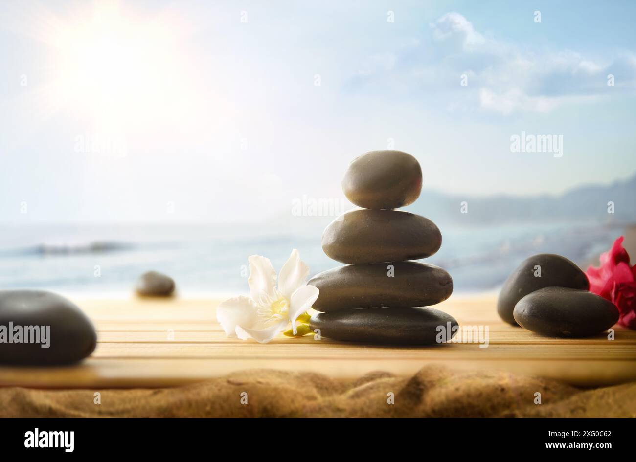 Health and body care with pile of black stones on wooden base on sand ...