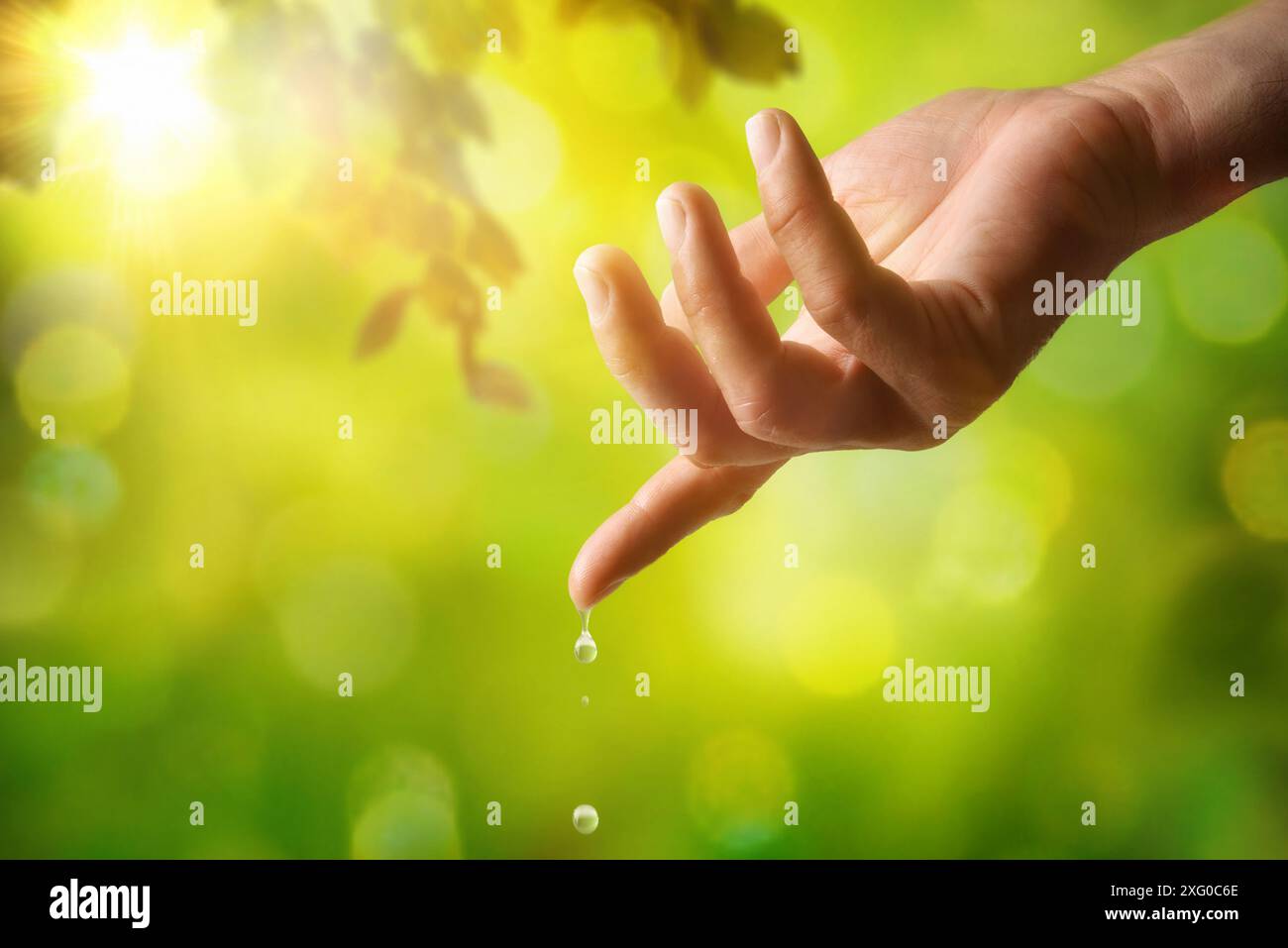Hand and water drops falling from finger with nature background with ...