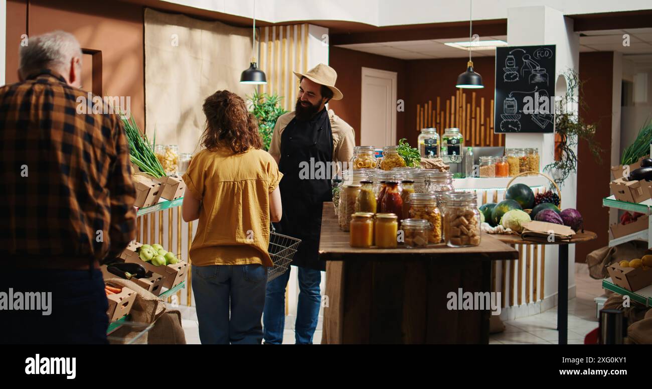 Owner greeting first customers at sustainable zero waste supermarket ...