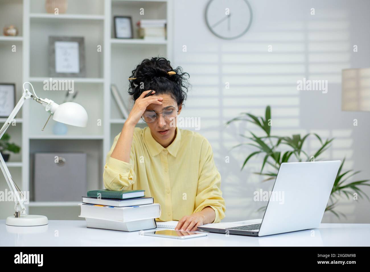 Young female student feeling stressed while studying with books and ...