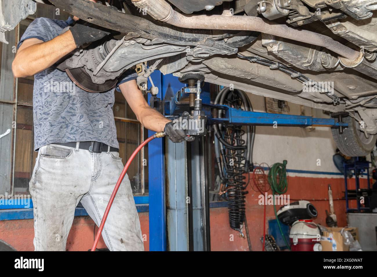 Mechanic repairing car lifted in garage lift Stock Photo - Alamy