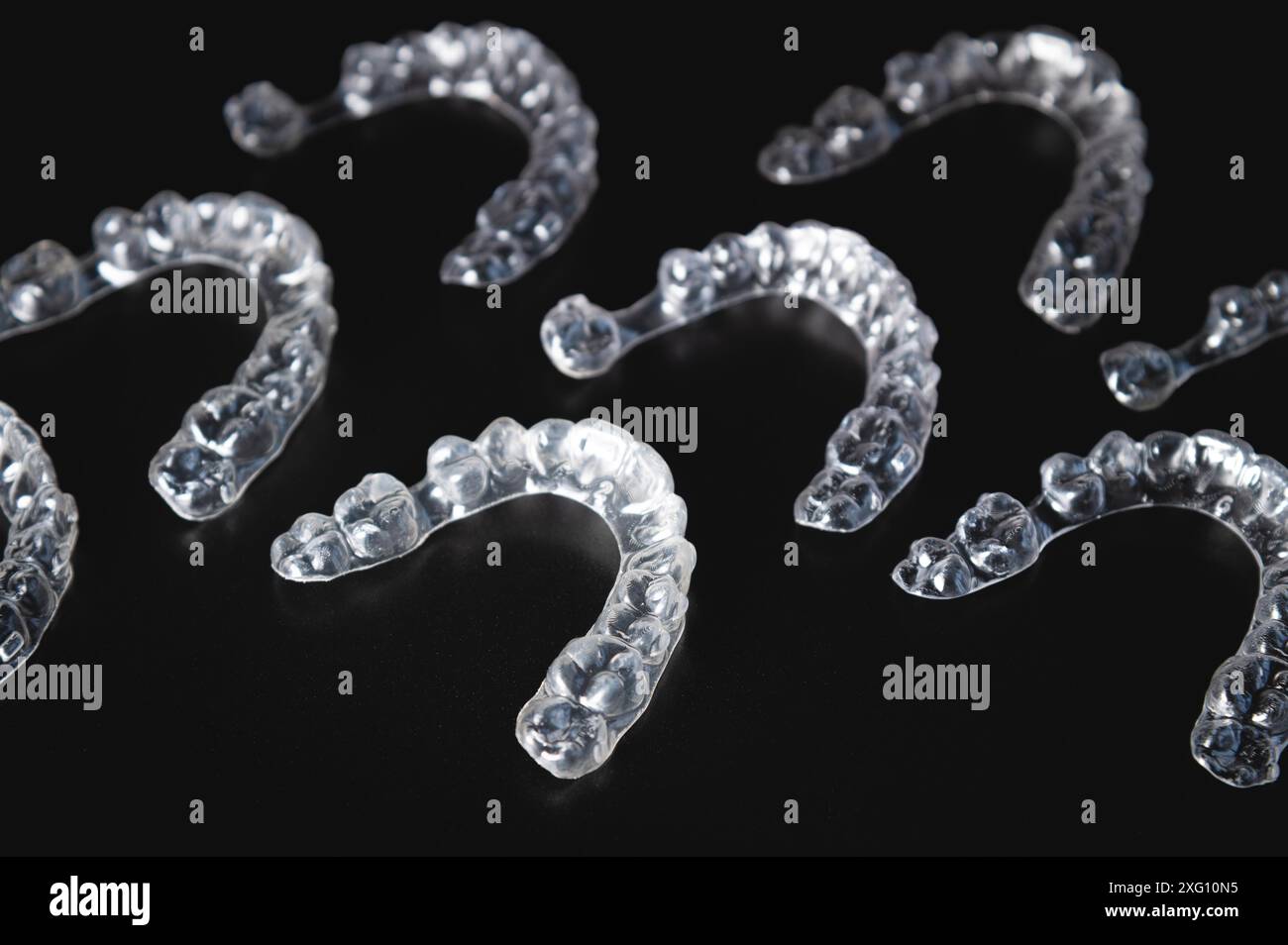 A pattern of invisible plastic aligners lie on a black background Stock ...