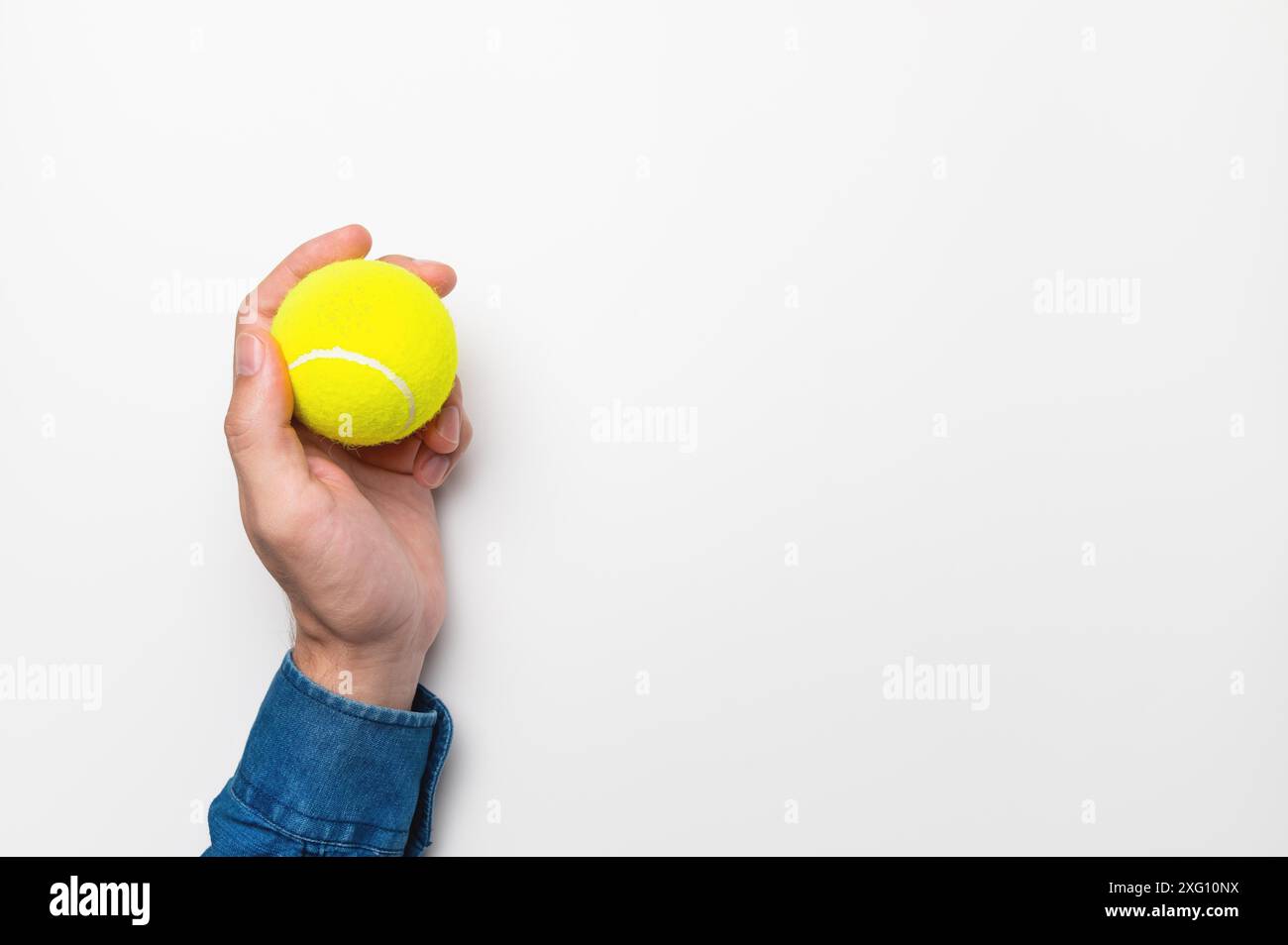 Yellow tennis ball in a male hand on a white background, a place for ...