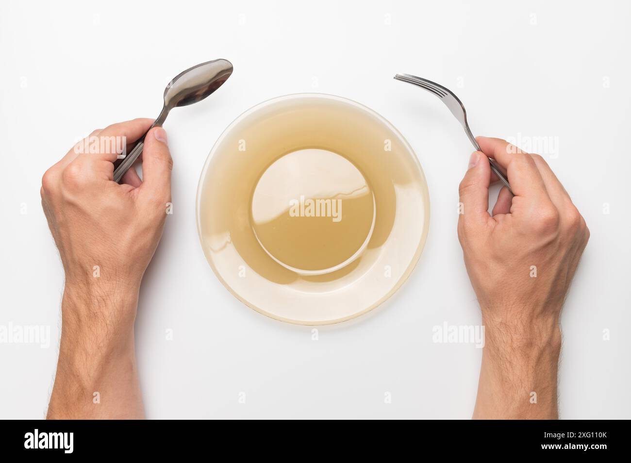 Male hands holding silver cutlery near empty plate on white, hungry ...
