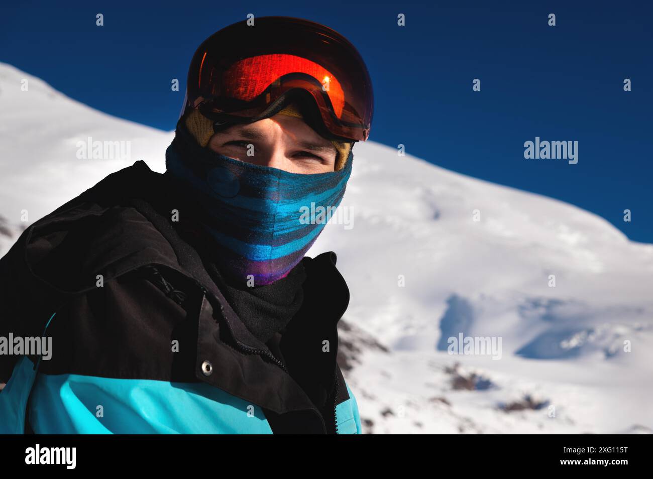 Portrait of a skier in the mountains without a ski mask with a scarf on ...