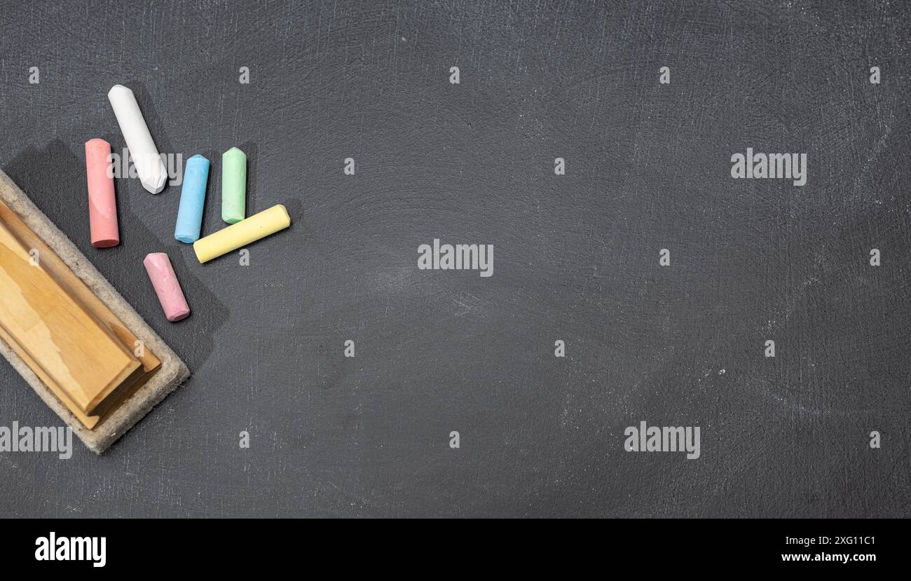 Group of colored chalk sticks and eraser on blackboard. Copy space ...