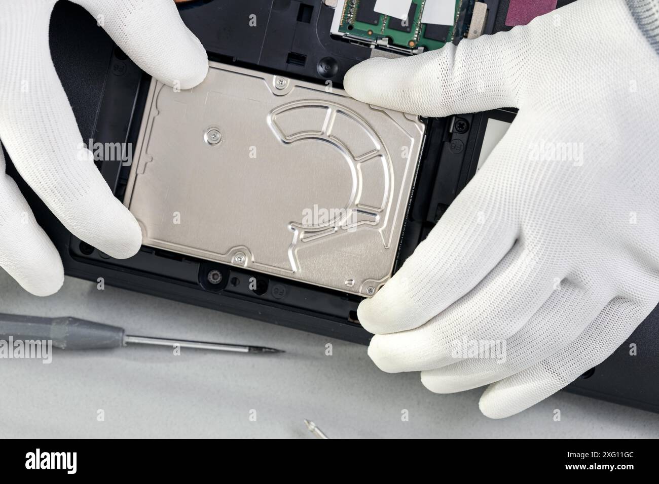 Technician hands removing an old mechanical hard disk from a laptop ...