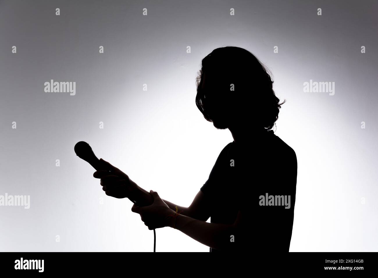 Silhouette of young singer holding wired microphone. Isolated on white ...
