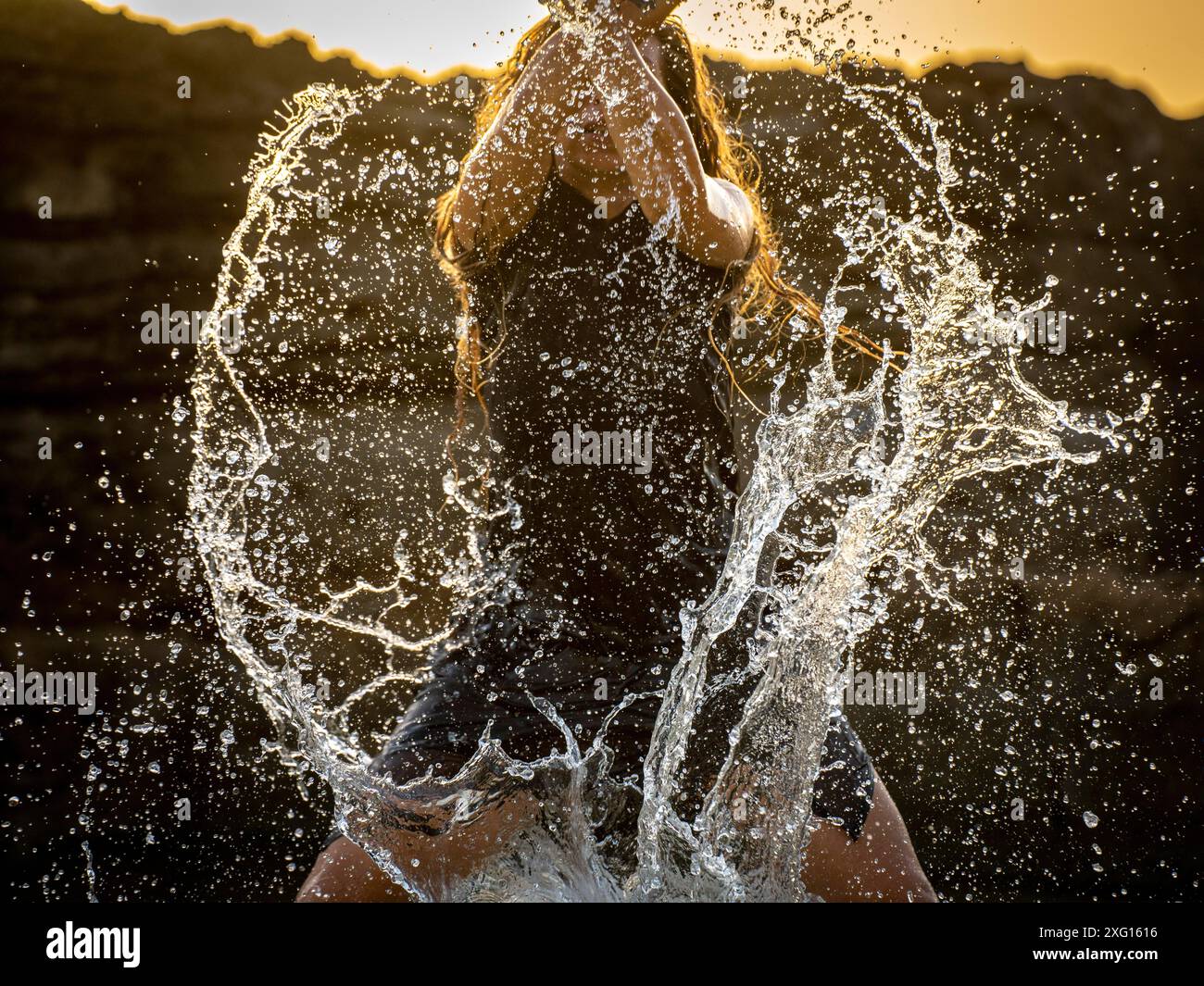Middle-aged woman dancing and throwing water in the air, Maioris beach ...