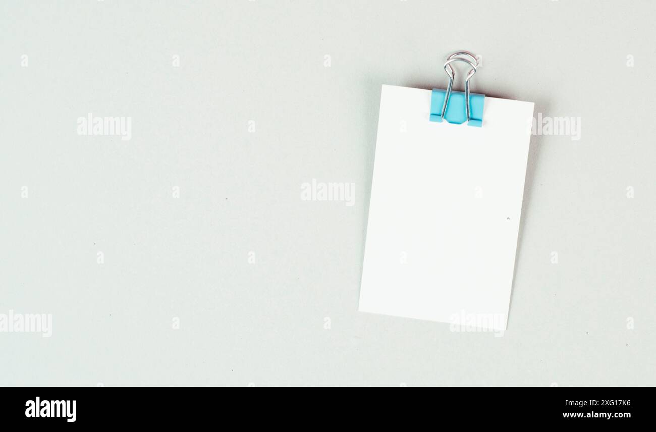 Blank white papers with a paperclip on a gray colored background, copy ...