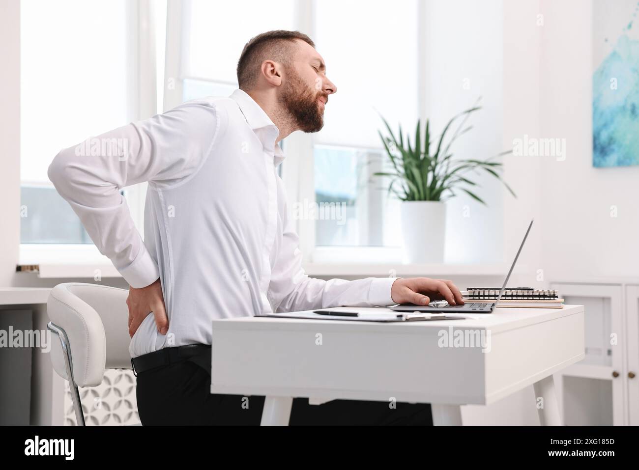 Man suffering from back pain in office. Symptom of poor posture Stock ...