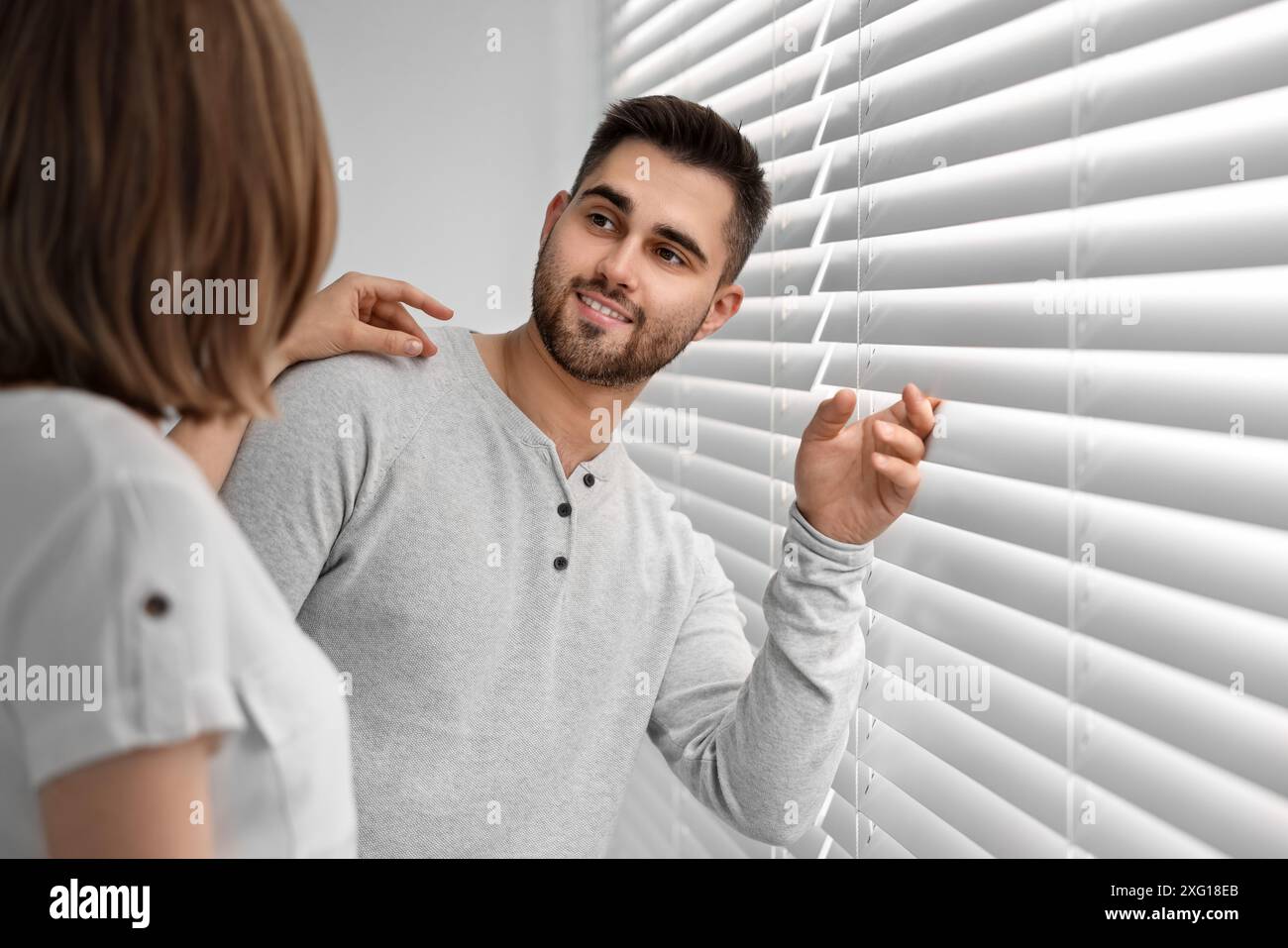 Young couple near window blinds at home Stock Photo - Alamy