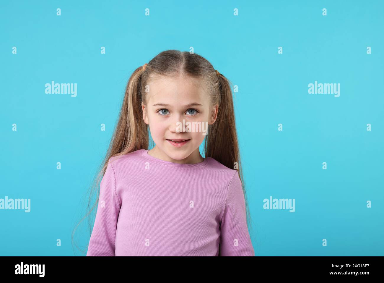 Portrait of cute little girl on light blue background Stock Photo - Alamy
