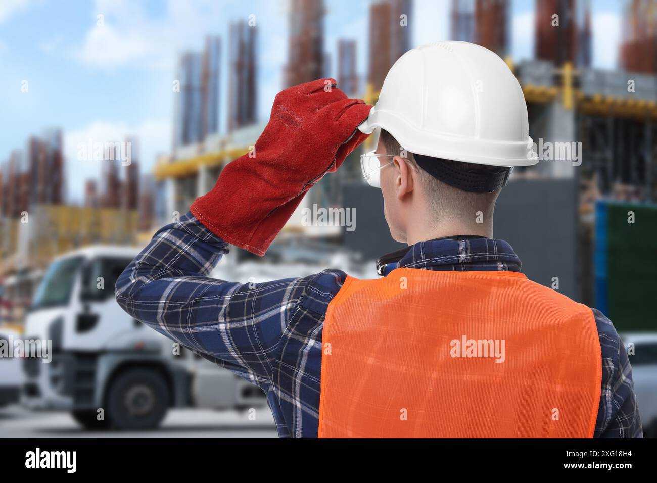Young man wearing safety equipment at construction site, back view ...