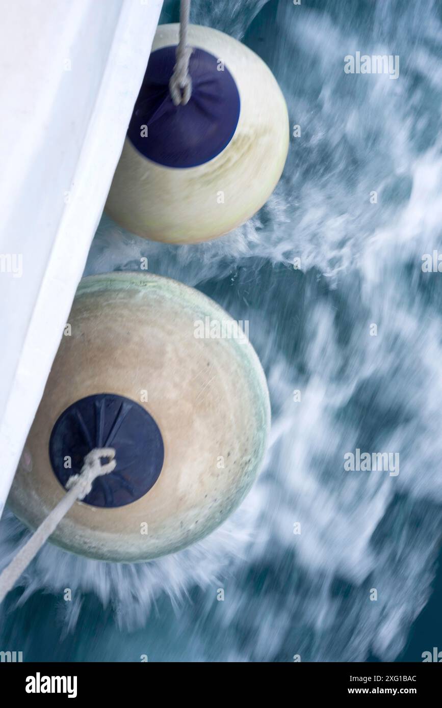 Two white fenders suspended between a boat and dockside for protection ...