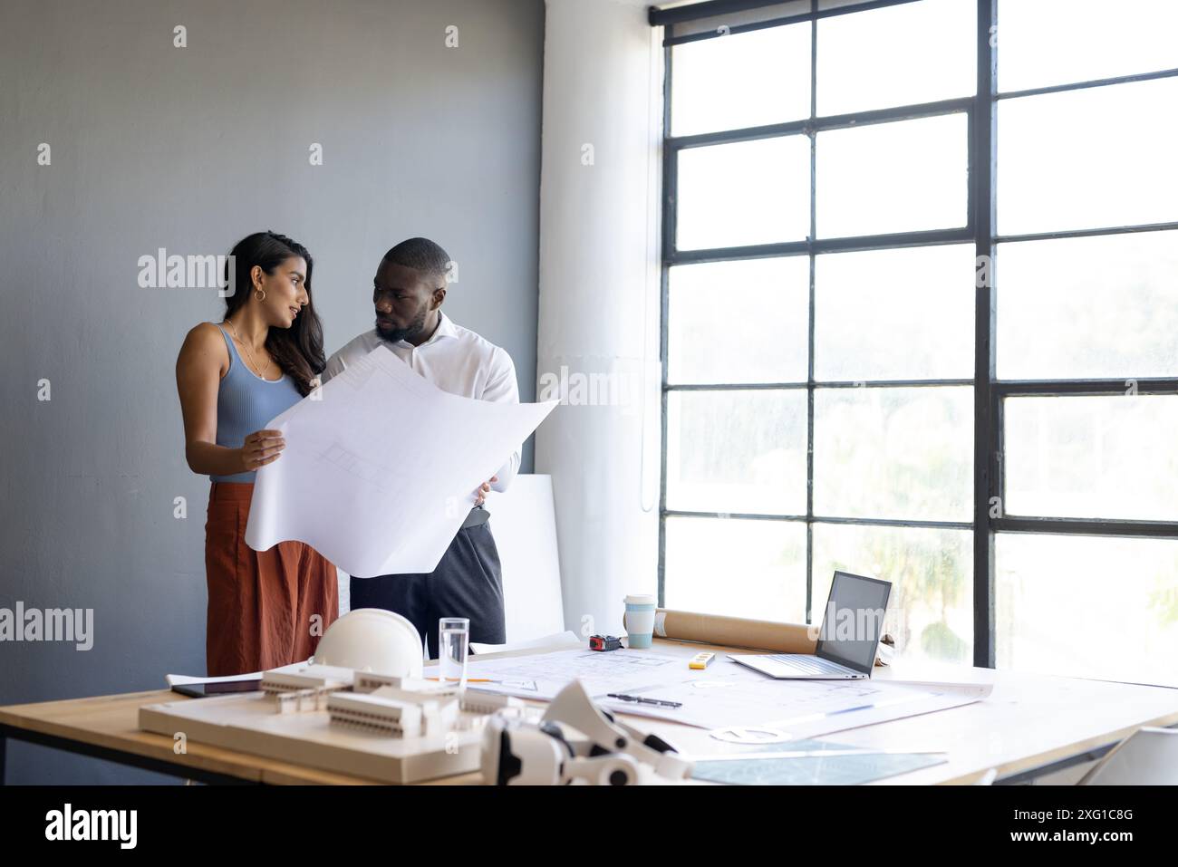 Architects reviewing blueprints in office, discussing project details ...