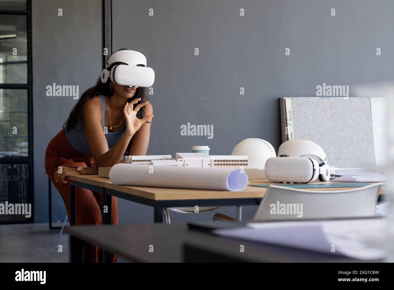 Using VR headset, woman exploring architectural model in modern office ...