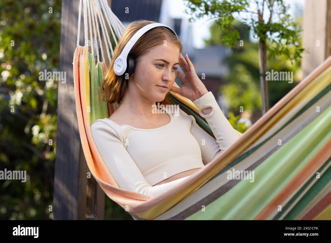 Relaxing in hammock, woman listening to music with headphones outdoors ...