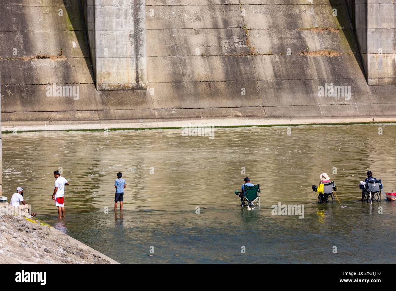Fishermen sit in the water below the spillway of the J. Edward Roush ...