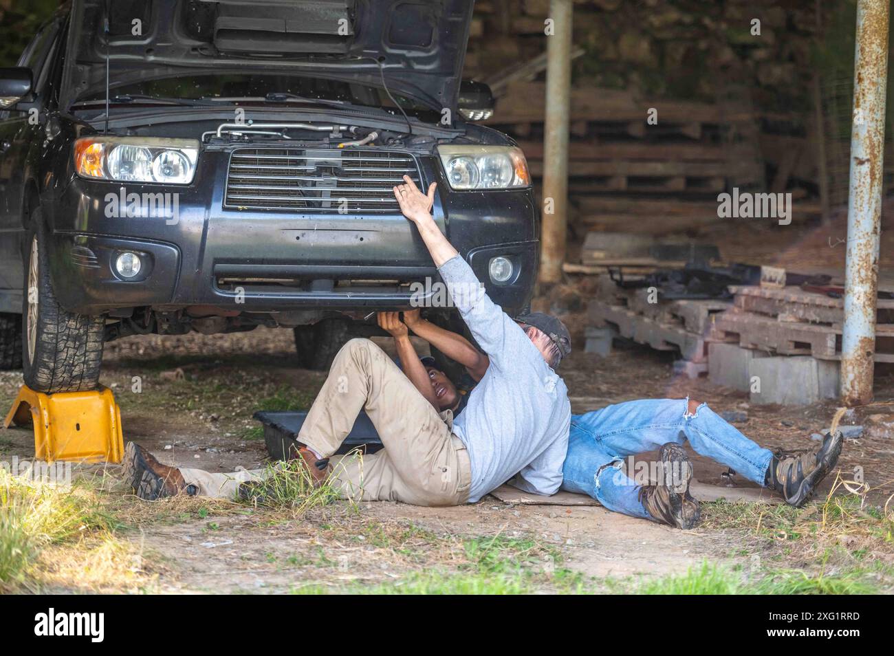 Father teaching son car repair auto mechanics underneath car in shop ...