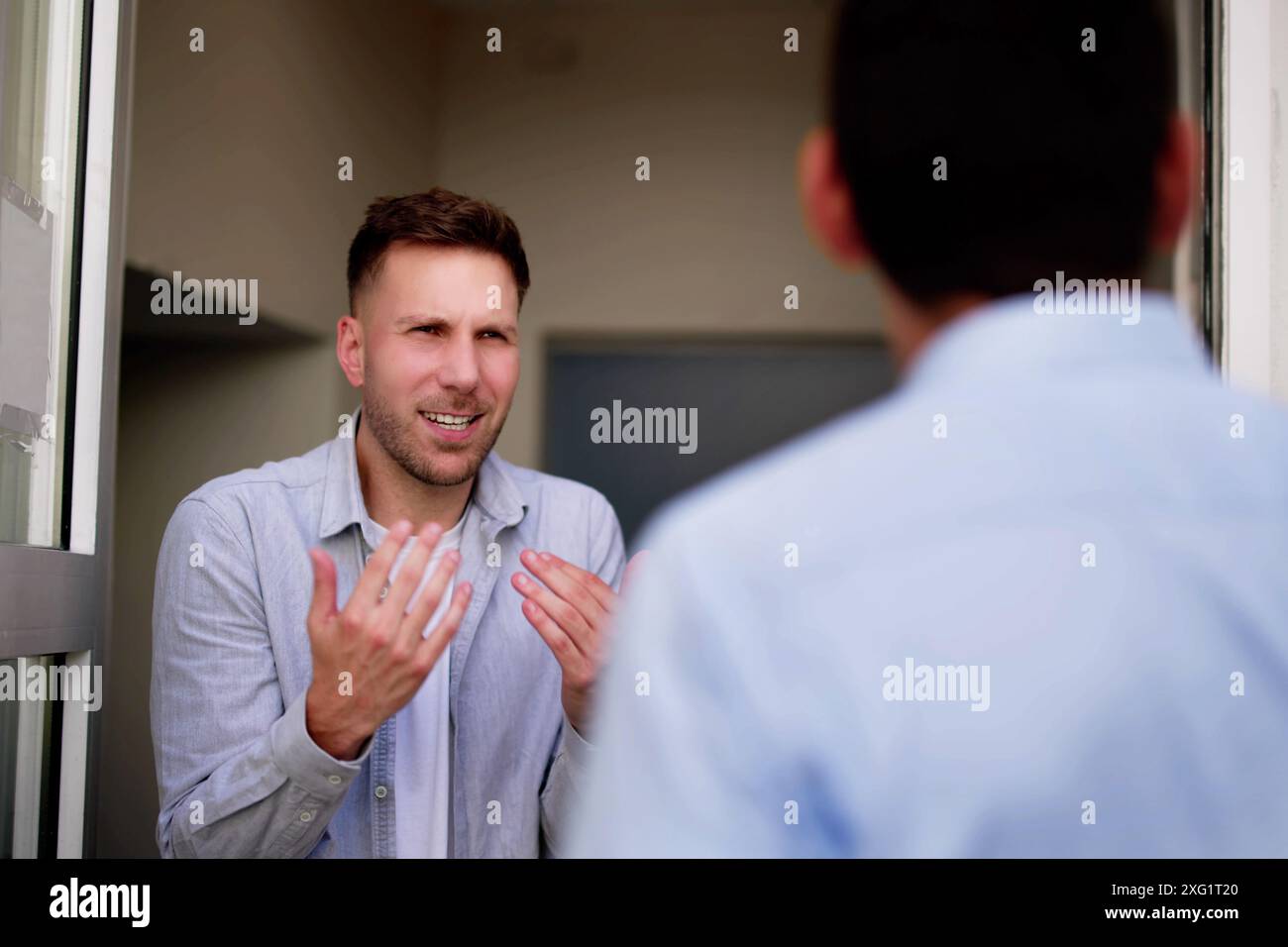 Stressed young man arguing with his Hispanic neighbor at the entrance ...
