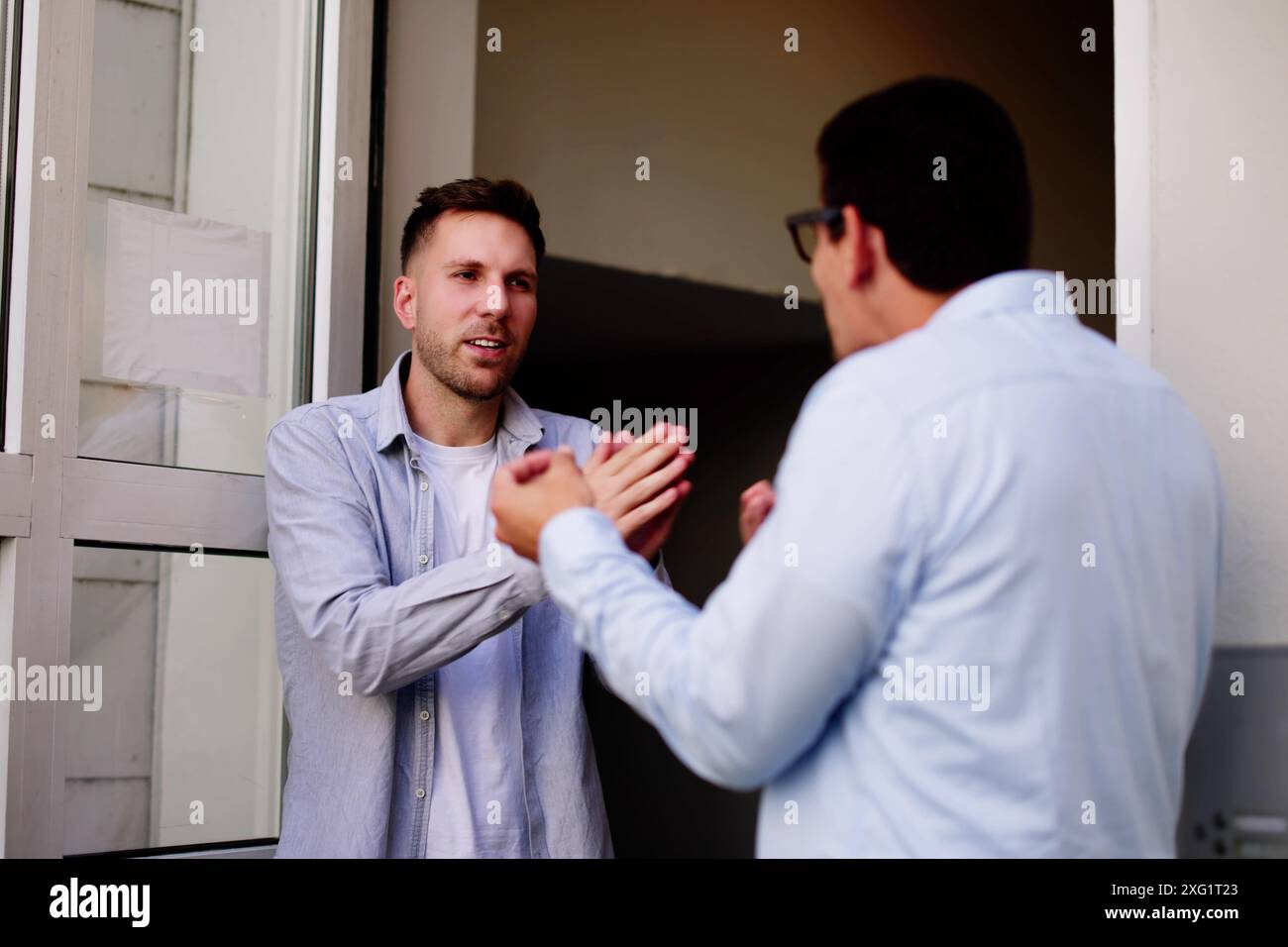 Two young men, one Hispanic, one Caucasian, arguing loudly at neighbor ...
