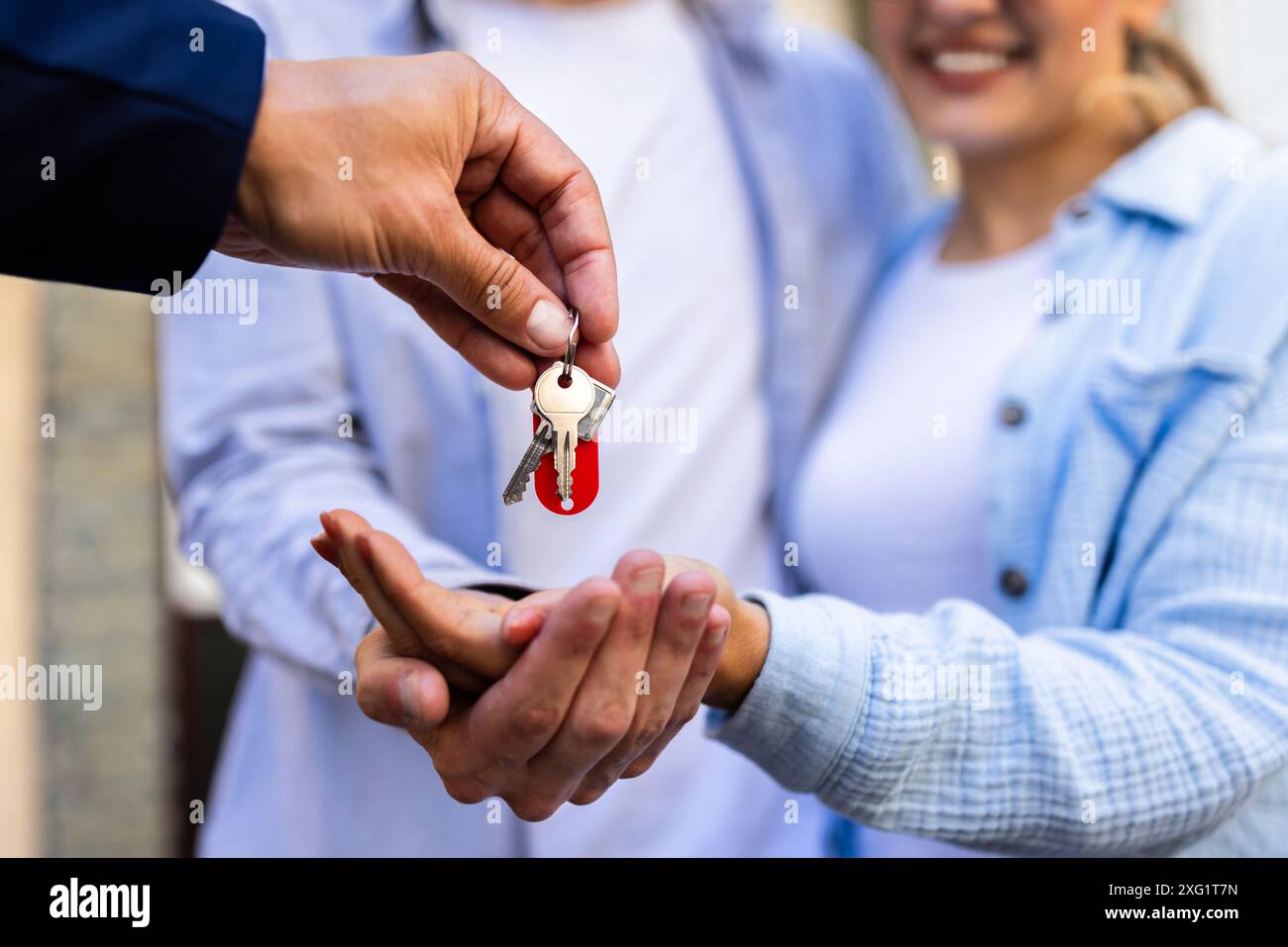 Real estate agent handing over keys to a young couple for their new ...