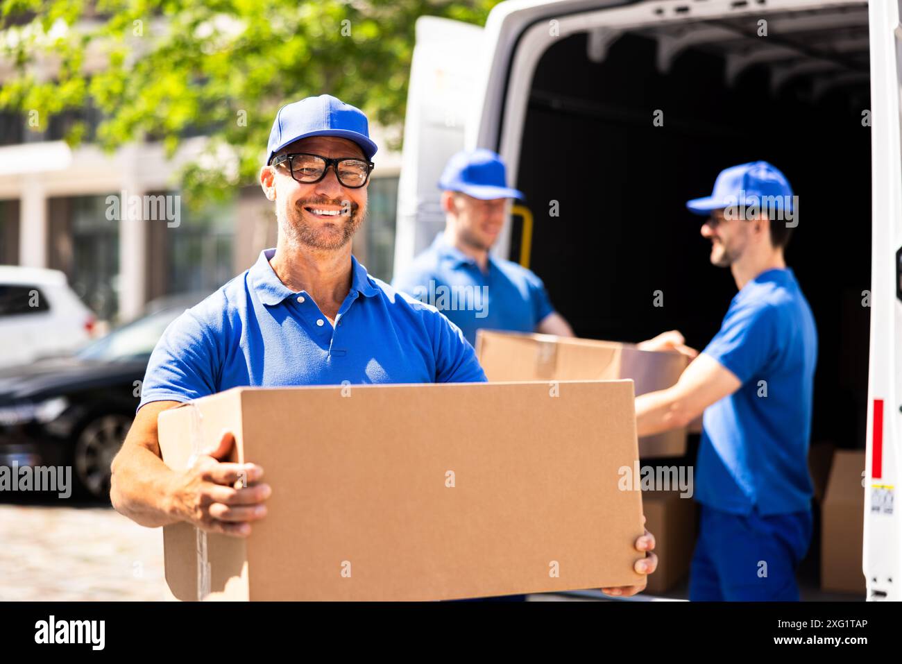 Efficient delivery men in blue uniforms are moving appliances into a ...