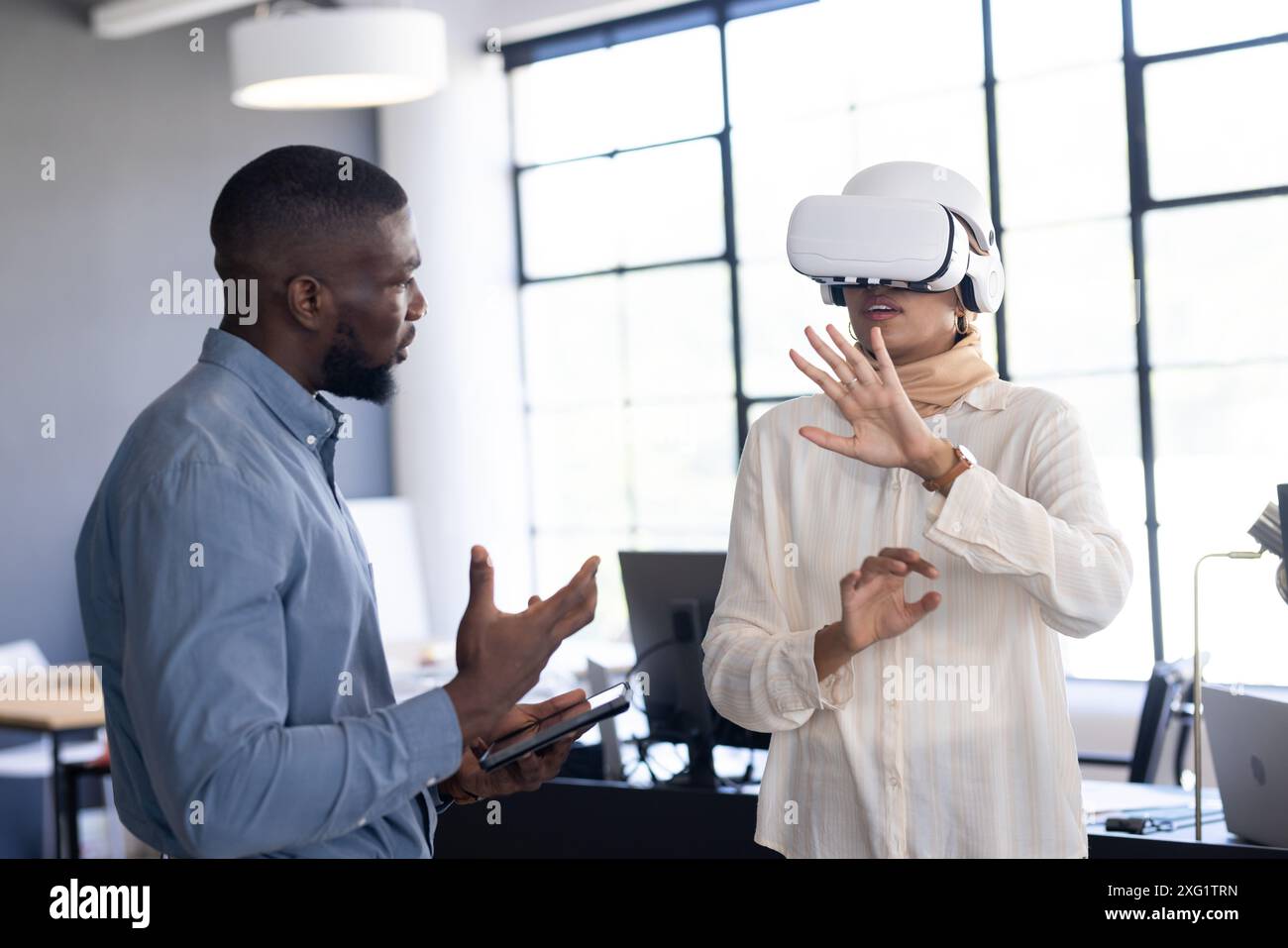 Using VR headset, woman interacting while man holding tablet in modern office Stock Photo - Alamy
