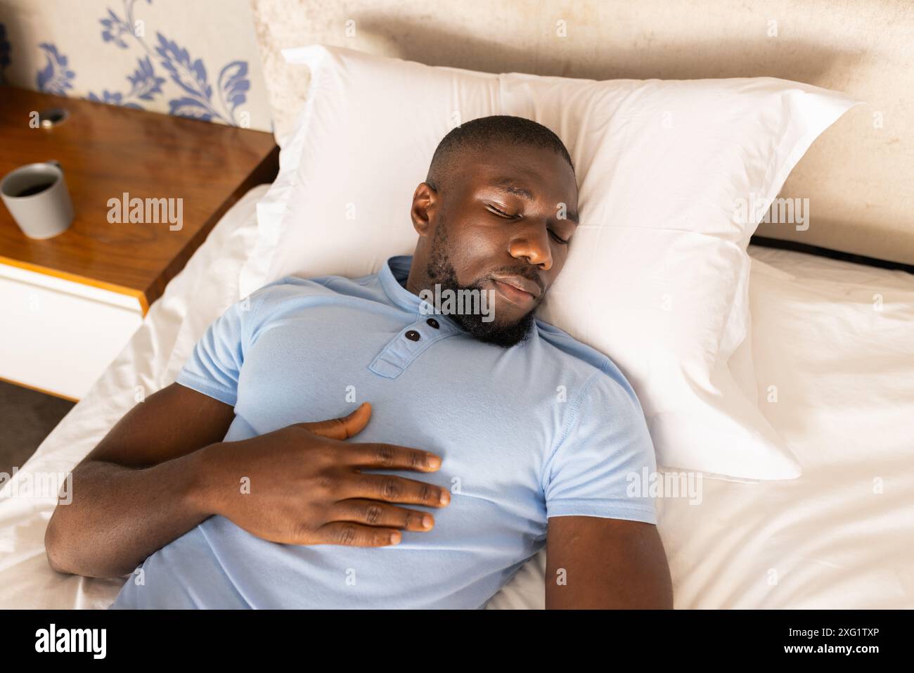 Relaxing in bed, African American man resting hand on chest, enjoying ...