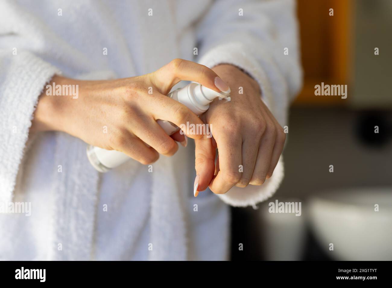 Applying lotion, woman in bathrobe moisturizing hands at home Stock ...