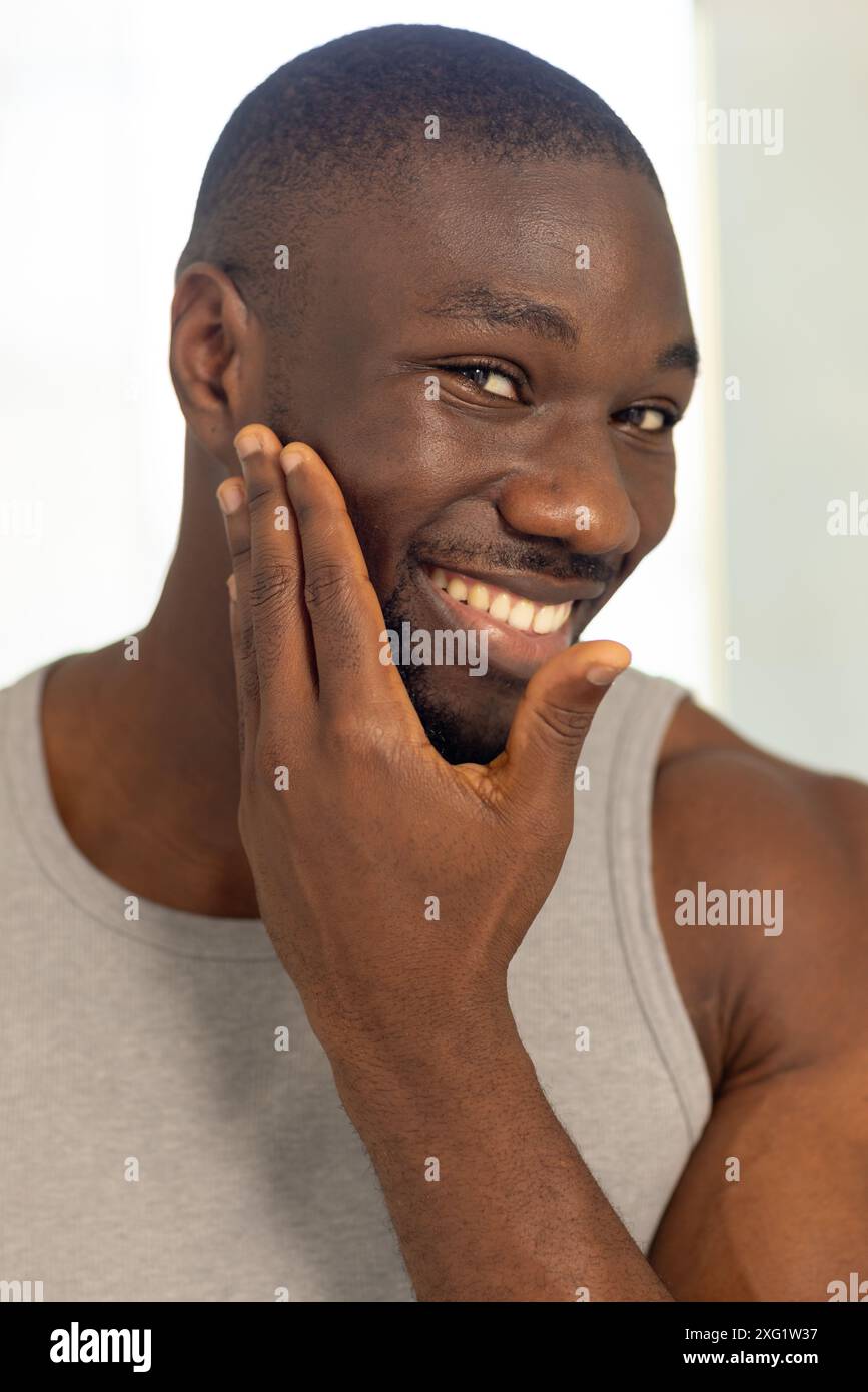 Smiling African American man touching face, enjoying skincare routine ...