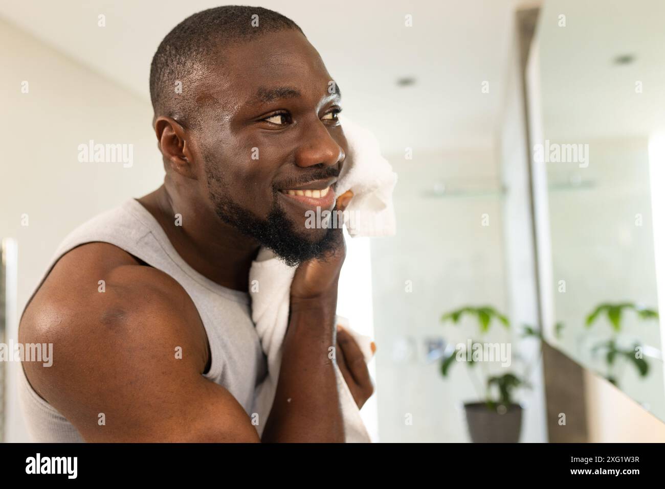 Smiling man drying face with towel in home bathroom, enjoying self-care ...